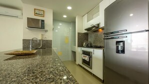 Cozinha moderna com bancadas de granito, eletrodomésticos de aço inoxidável e armários brancos.
