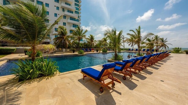 Área de piscina com espreguiçadeiras e palmeiras.