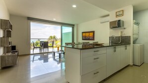 Cozinha moderna com ilha de vidro, armários brancos e vista para uma varanda.