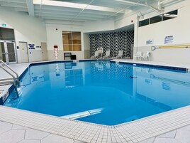 Piscina interna com água cristalina, paredes azulejadas e um detalhe de parede xadrez.