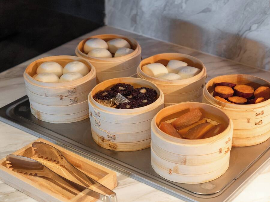 Uma bandeja com vários vapores de bambu contendo diversos alimentos.