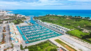 Vista aérea de uma marina com vários barcos atracados, rodeada por edifícios residenciais e vegetação.