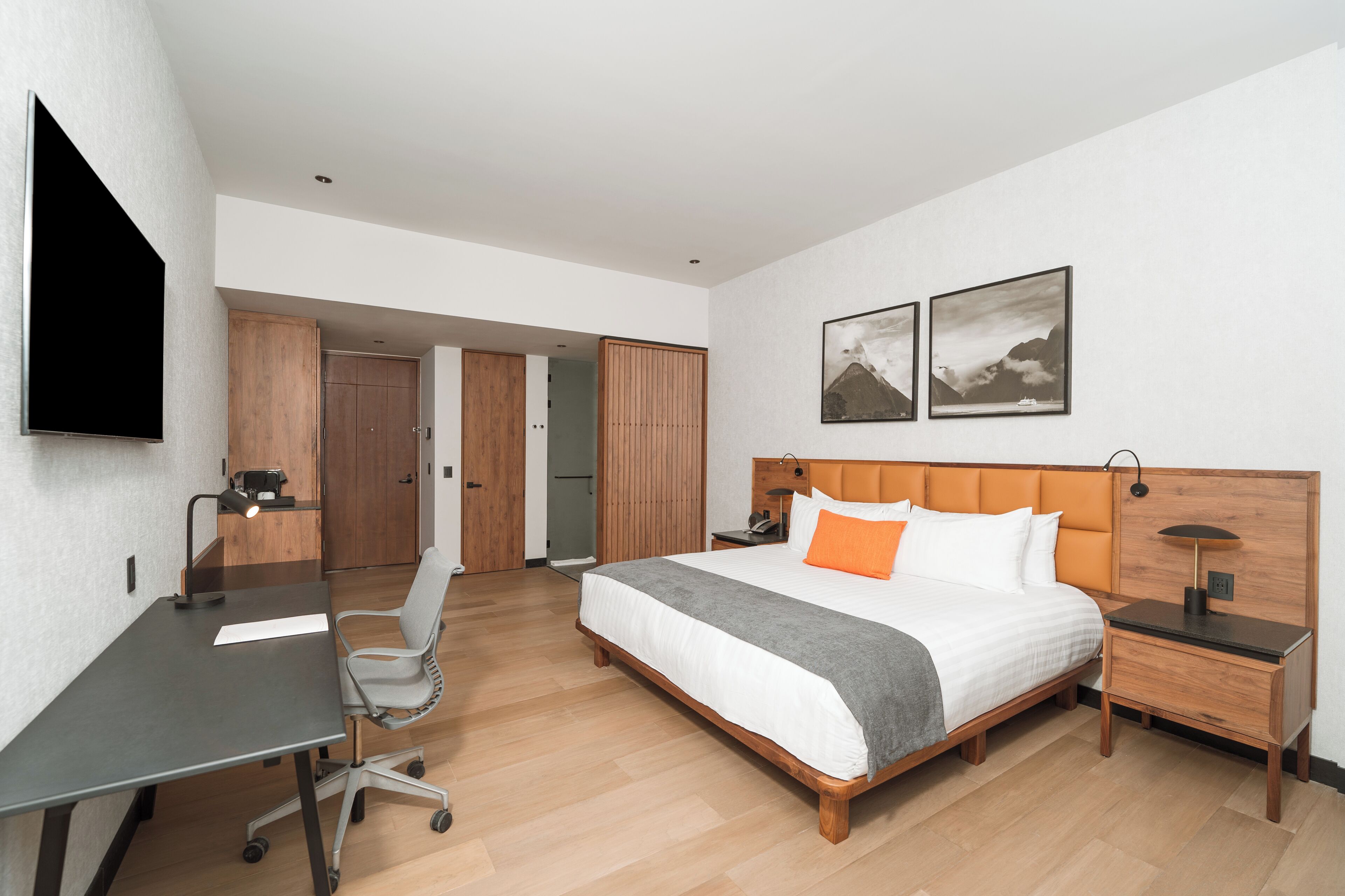 Quarto de hotel moderno com uma cama grande, uma mesa e uma cadeira.