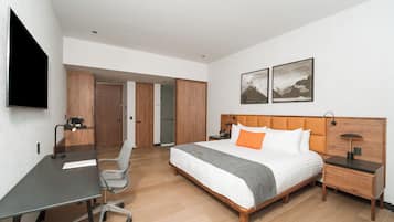 Quarto de hotel moderno com uma cama grande, uma mesa e uma cadeira.