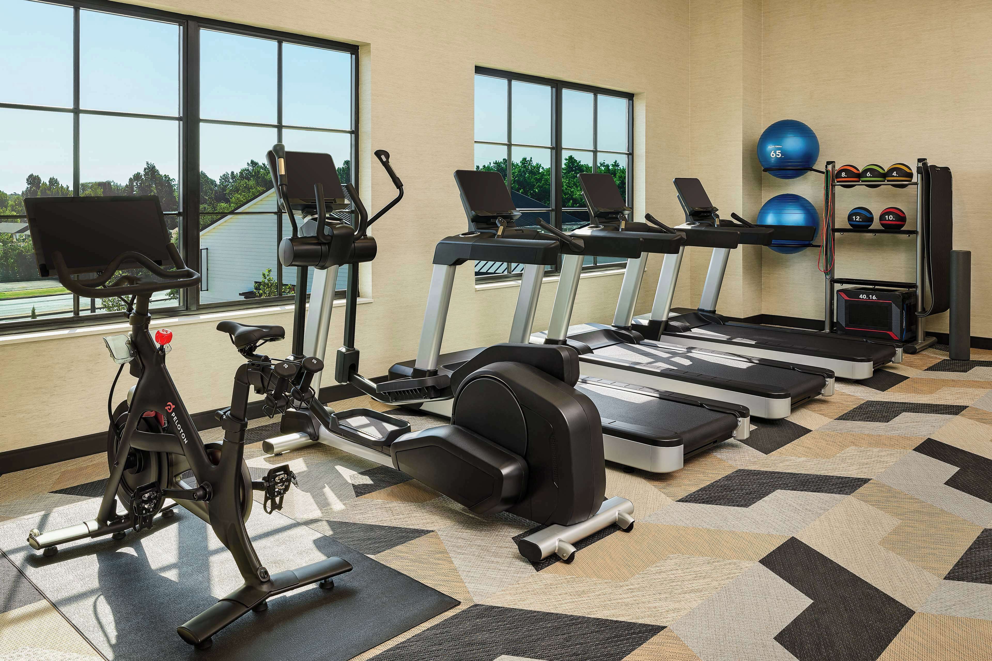 Uma academia com esteiras, elípticos e bolas de exercício.