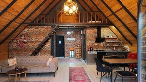 Quarto no estilo sótão com cama mezanina, sofá, mesa de jantar e cozinha.