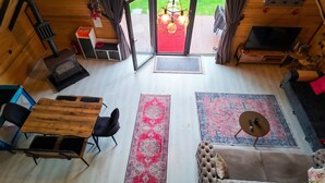 Interior acolhedor de uma cabana com sala de jantar, sofá, televisão e lareira.