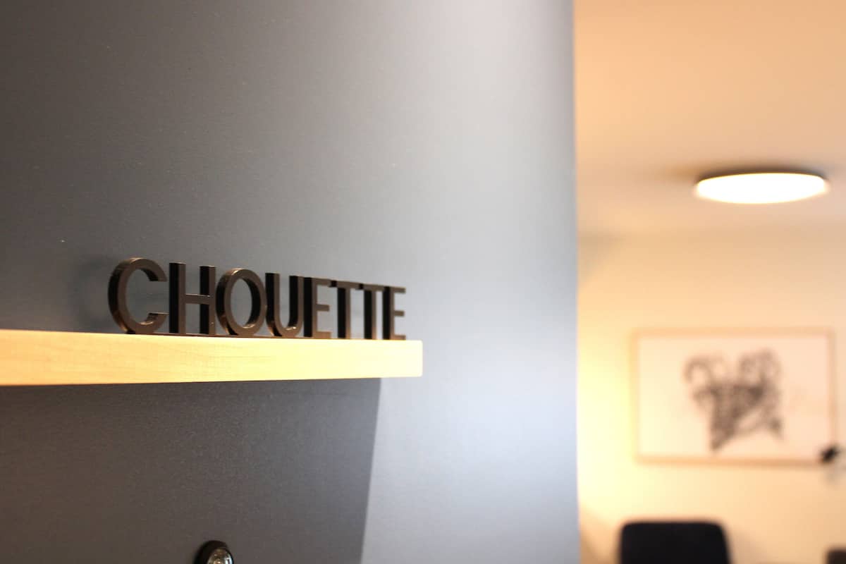 Um letreiro com a palavra 'CHOUETTE' em uma parede.