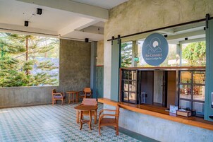 Uma área de recepção com uma grande janela, móveis de madeira e uma placa com o nome "ProConnect Nature Lodge Pai".