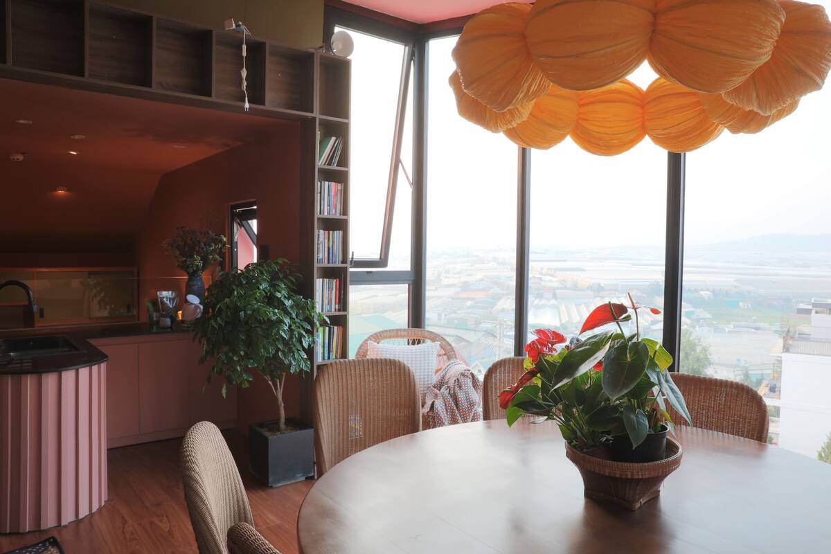 Uma cozinha moderna com ilha integrada, área de refeições com mesa redonda e uma grande janela com vista para a cidade.