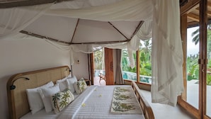 Quarto com cama, dossel e vista para uma piscina e vegetação tropical.