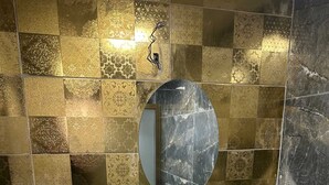 Um banheiro com pia de mármore, azulejos com padrão dourado e um espelho.