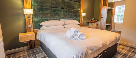 Uma cama bem arrumada com carpete xadrez, cabeceira de madeira e mesa de cabeceira pequena com abajur.