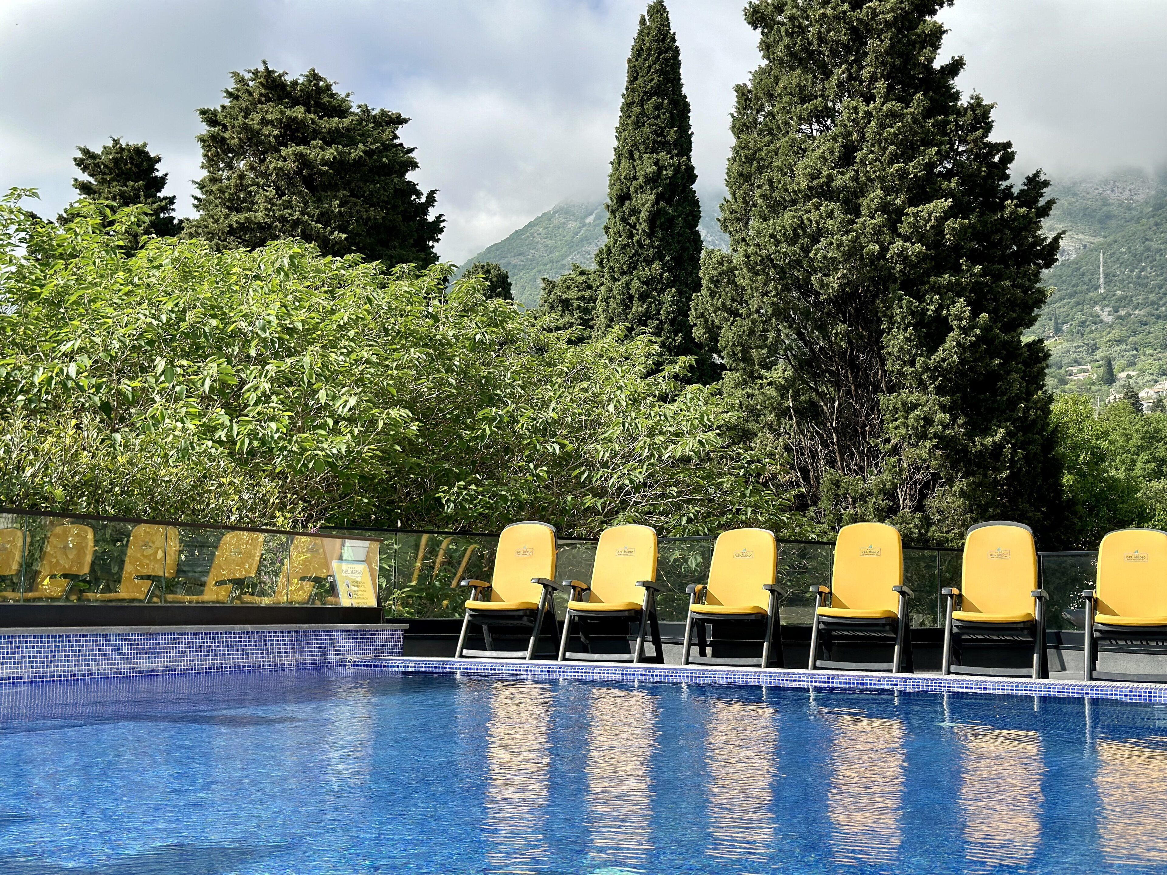 Piscina com borda revestida e cadeiras amarelas ao longo da lateral.