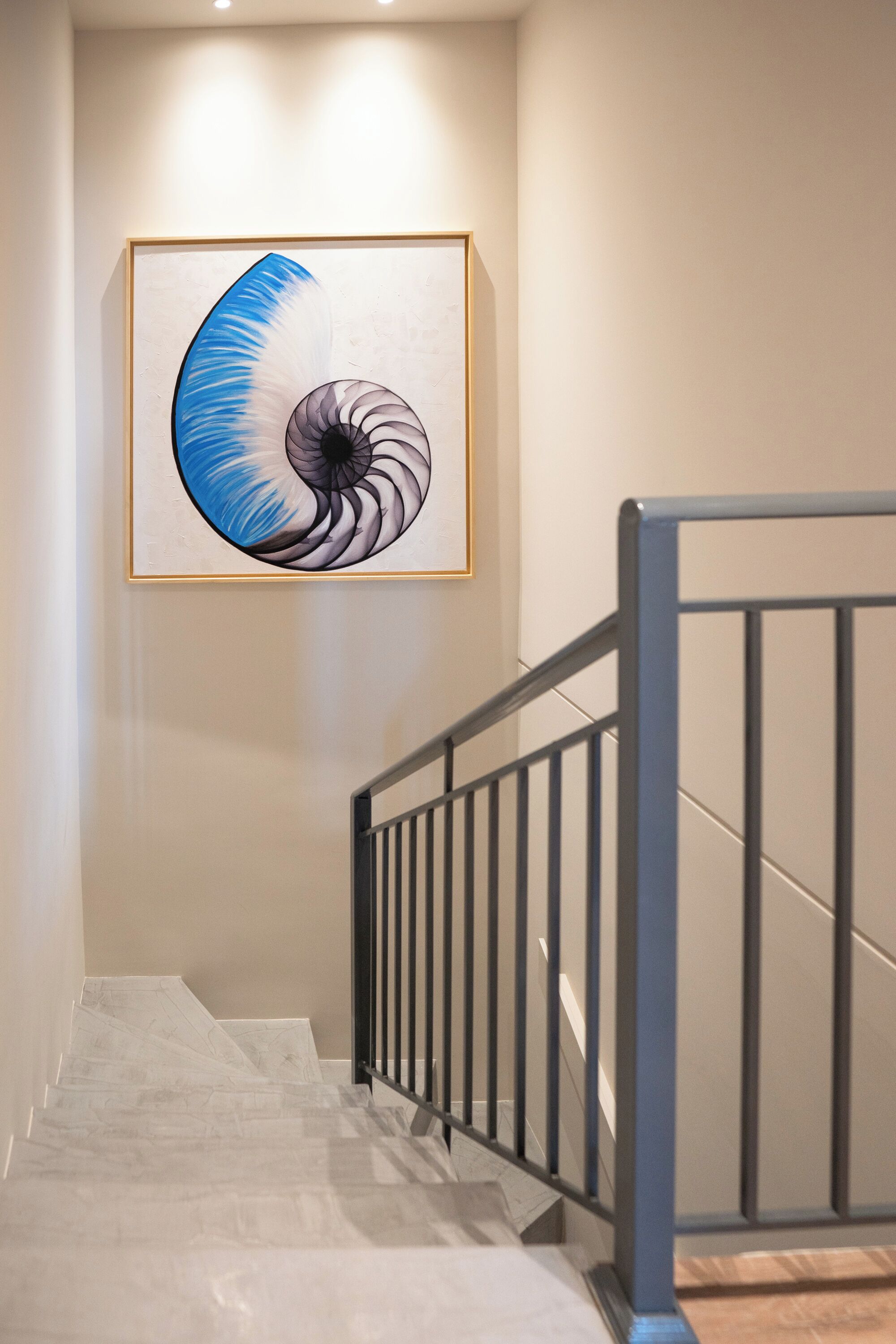 Uma escadaria com corrimão de metal e uma obra de arte emoldurada na parede.