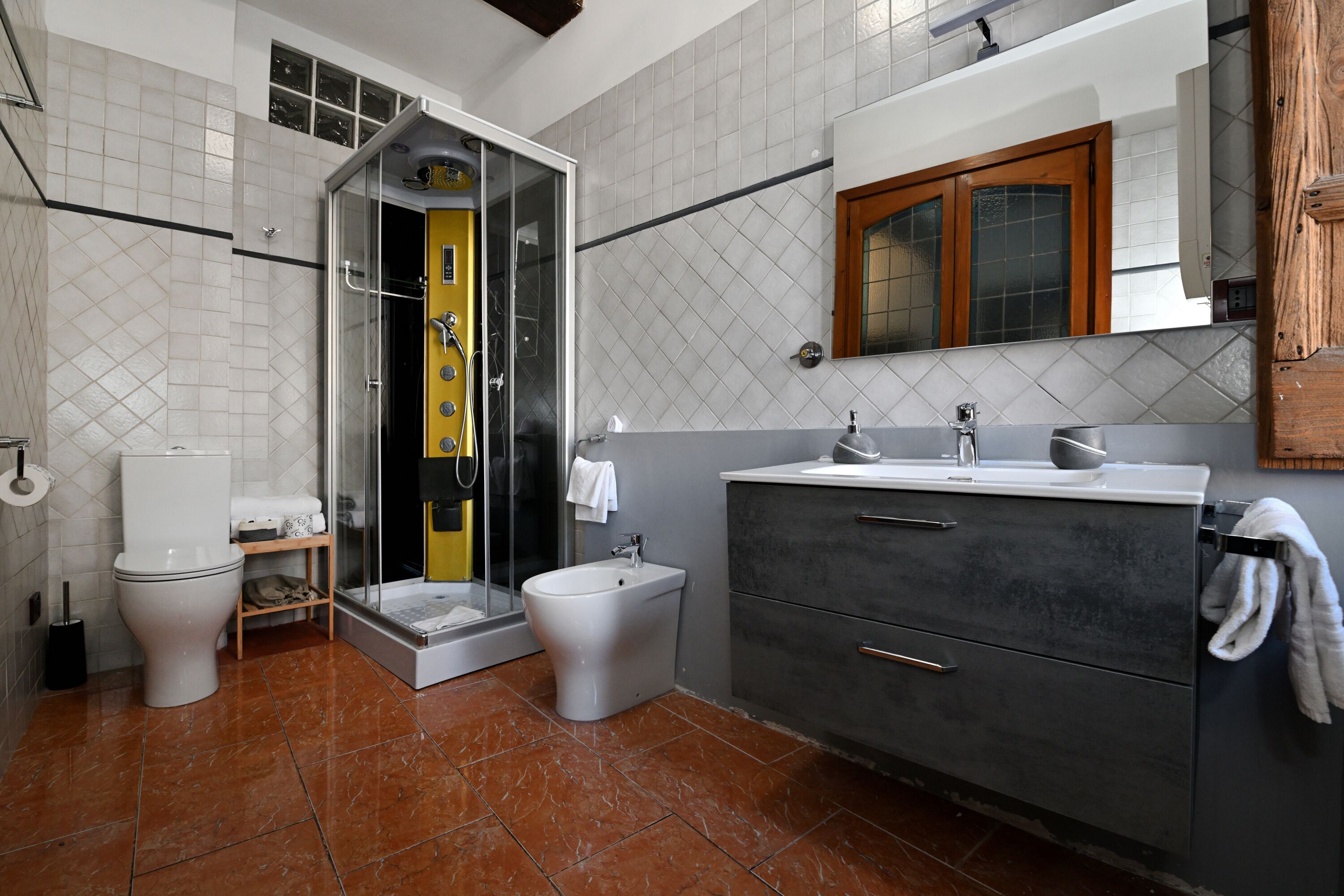 Casa de banho moderna com chuveiro, sanita, bidé e toucador.