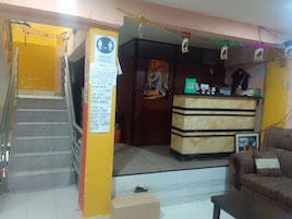 Um saguão de hotel com balcão de recepção, escada e sofá.