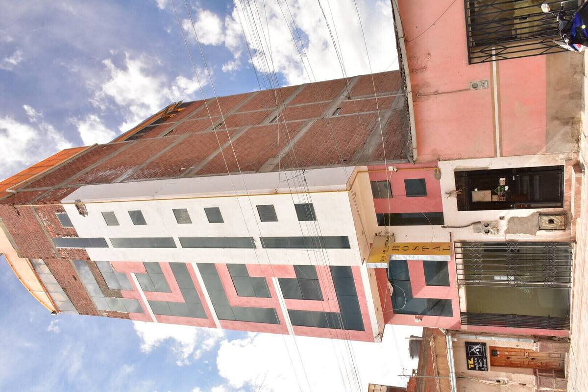Um edifício de vários andares com fachada geométrica marcante, combinando tijolo e paredes brancas.