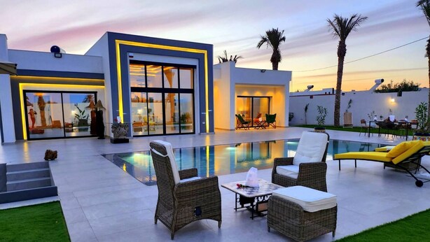 Uma casa moderna com piscina, área de estar ao ar livre e gramado bem cuidado.