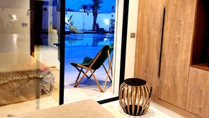 Sala de estar moderna com porta de vidro que dá para uma área de piscina externa, um armário de madeira e um abajur de fibra.