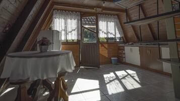 Um quarto de sótão espaçoso com teto inclinado, uma mesa de jantar com cadeiras, uma área de cozinha e vista através de uma porta.