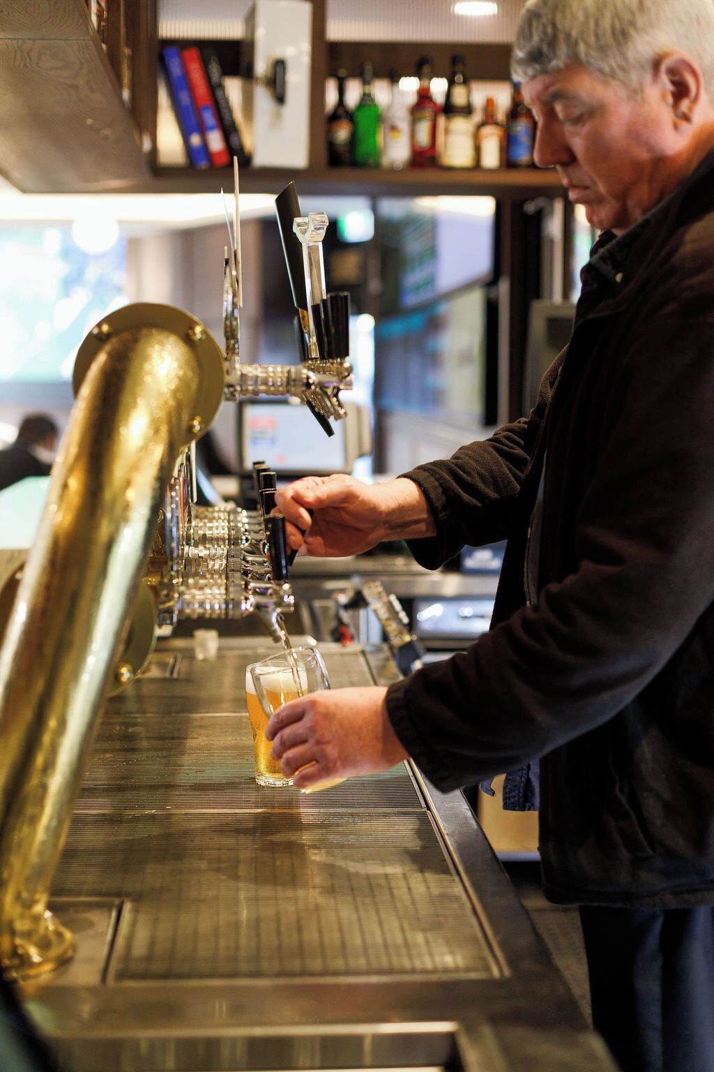 Alguém servindo cerveja de uma torneira num copo.