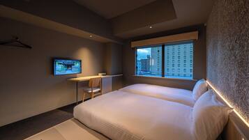 Quarto de hotel moderno com duas camas, uma escrivaninha e uma grande janela com vista para a cidade.