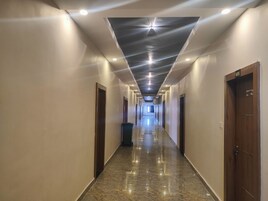 Corredor longo e bem iluminado, com portas em ambos os lados, que dá acesso a quartos.