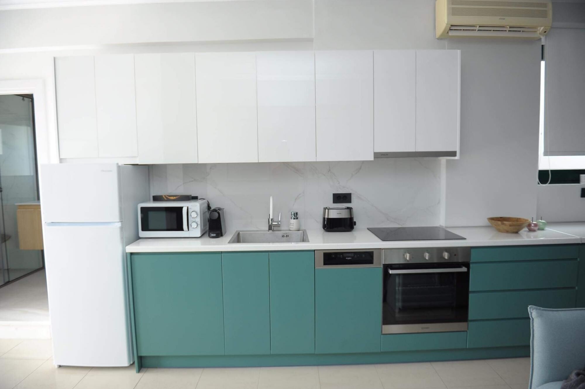 Uma cozinha moderna com armários brancos, micro-ondas, torradeira e máquina de lavar louça.