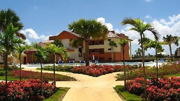 Um hotel com um pátio central, palmeiras e flores vermelhas.