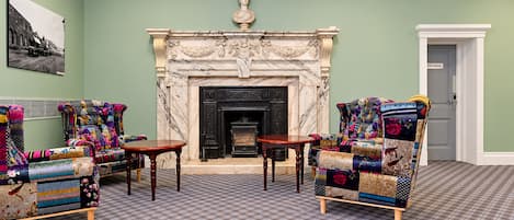 Quarto com lareira, duas poltronas, uma mesa pequena e uma porta com a inscrição 'Albert Room'.