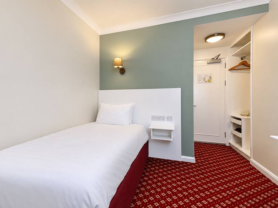 Quarto de hotel com cama, guarda-roupa e espelho.
