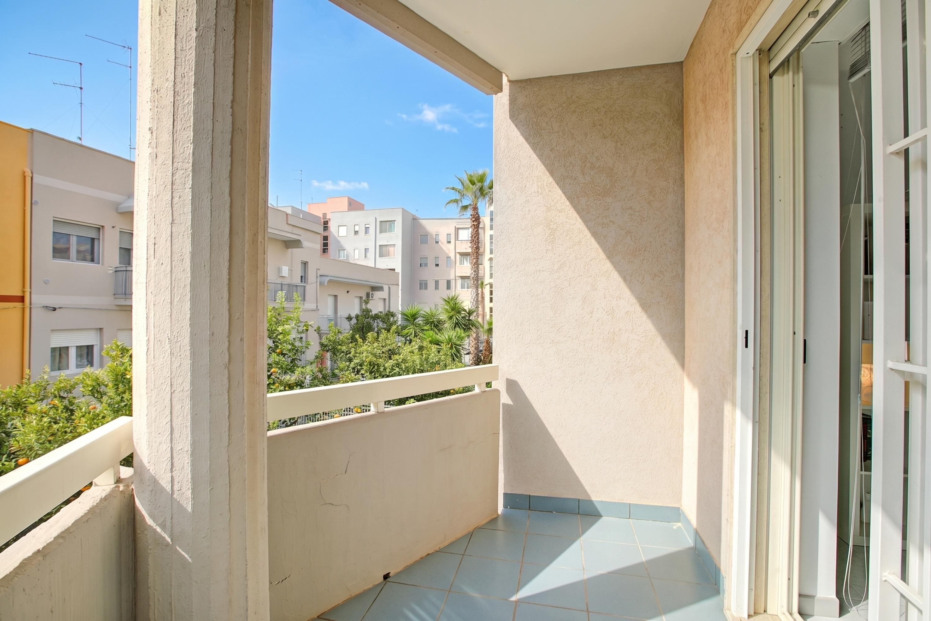 Varanda com vista para edifícios vizinhos e vegetação.
