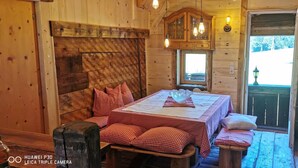 Interior acolhedor de uma cabana de madeira, com uma cama, uma mesa e um banco.
