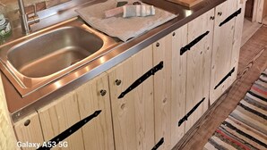 Uma cozinha com armários de madeira, uma pia de aço inoxidável e bancada com utensílios de cozinha.