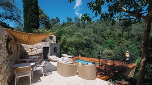 Um pátio externo com piso de pedra, móveis de vime e área de piscina.