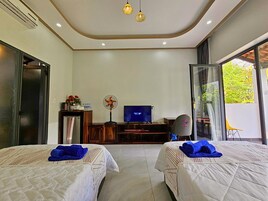 Quarto de hotel com duas camas, televisão, escrivaninha e uma janela grande.