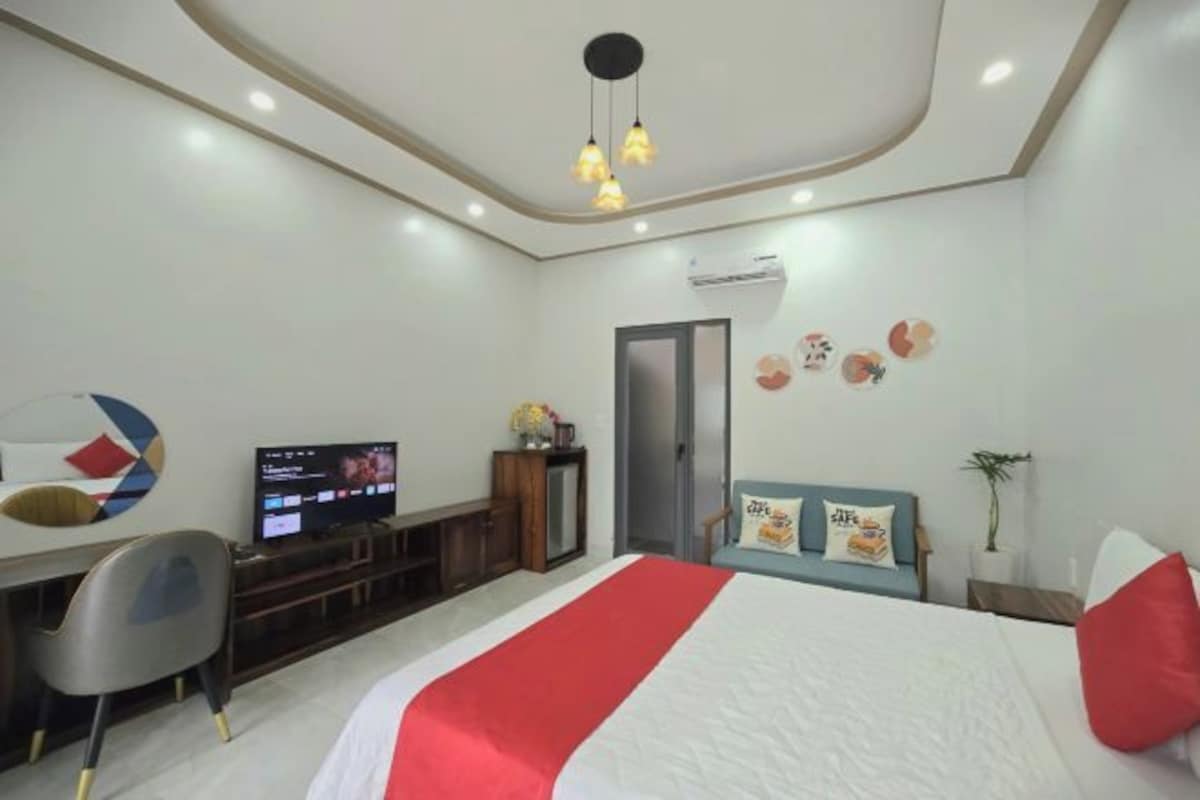 Quarto de hotel moderno com cama, escrivaninha, televisão e arte decorativa na parede.