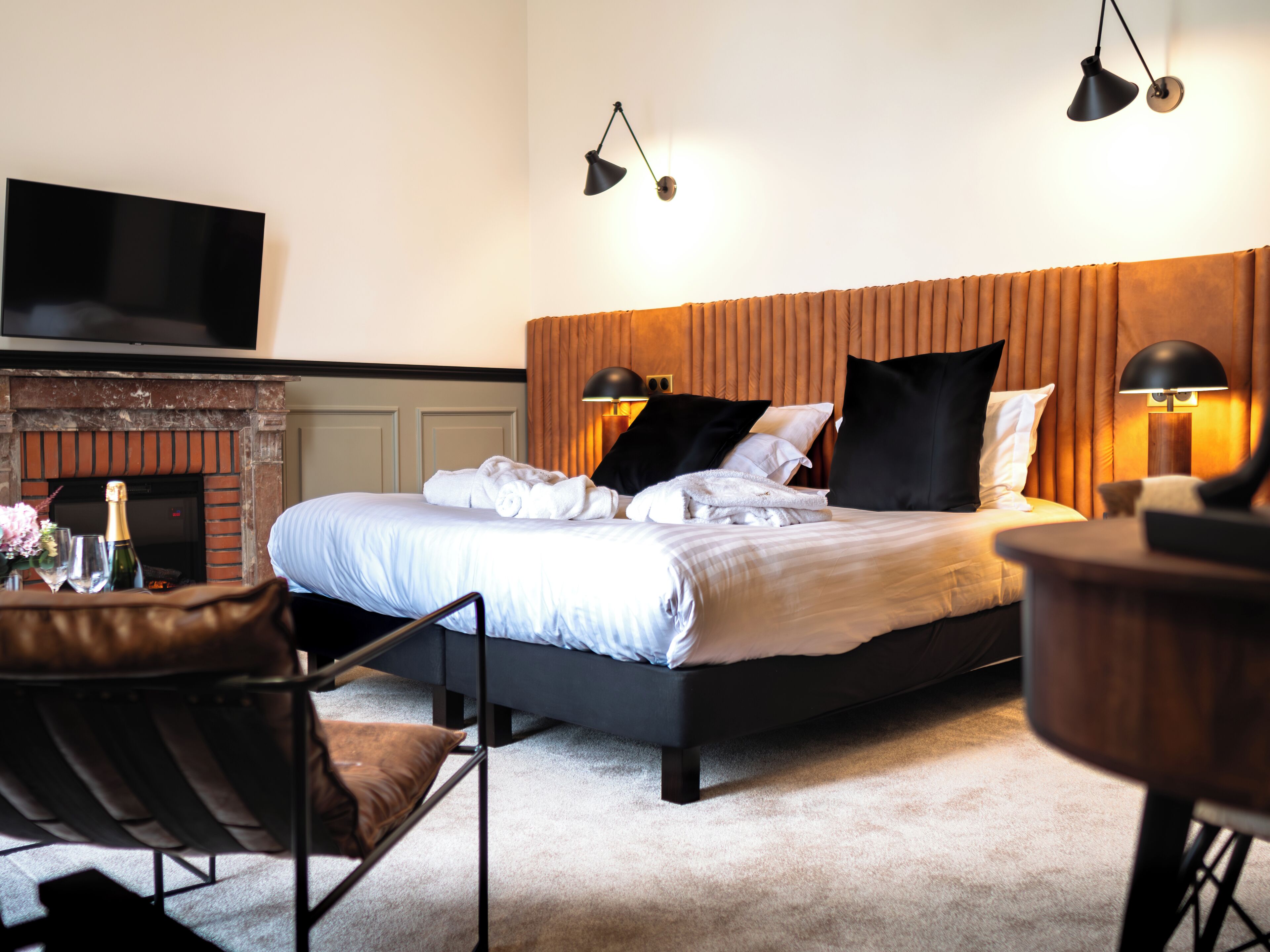 Quarto moderno com uma cama grande, lareira e televisão de tela plana.