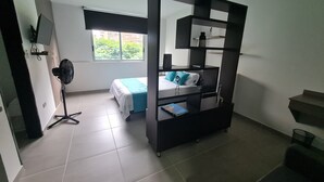 Quarto moderno com cama, ventilador e janela com vista para áreas verdes.