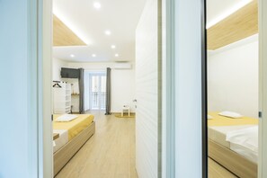 Quarto de hotel moderno com duas camas, uma pequena mesa e uma televisão.
