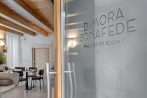 Um interior moderno com uma porta de vidro exibindo o nome "DIMORA BONAFEDE" e "IBLA DESIGN ROOMS".
