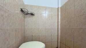 Casa de banho com sanita, paredes em azulejo e chão estampado.