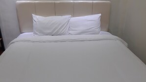 Uma cama com cabeceira e duas almofadas.