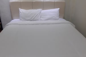 Uma cama com cabeceira e duas almofadas.