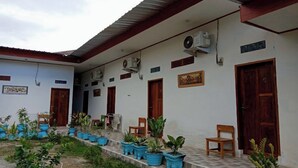 Um edifício com várias portas, aparelhos de ar condicionado e vasos de plantas.
