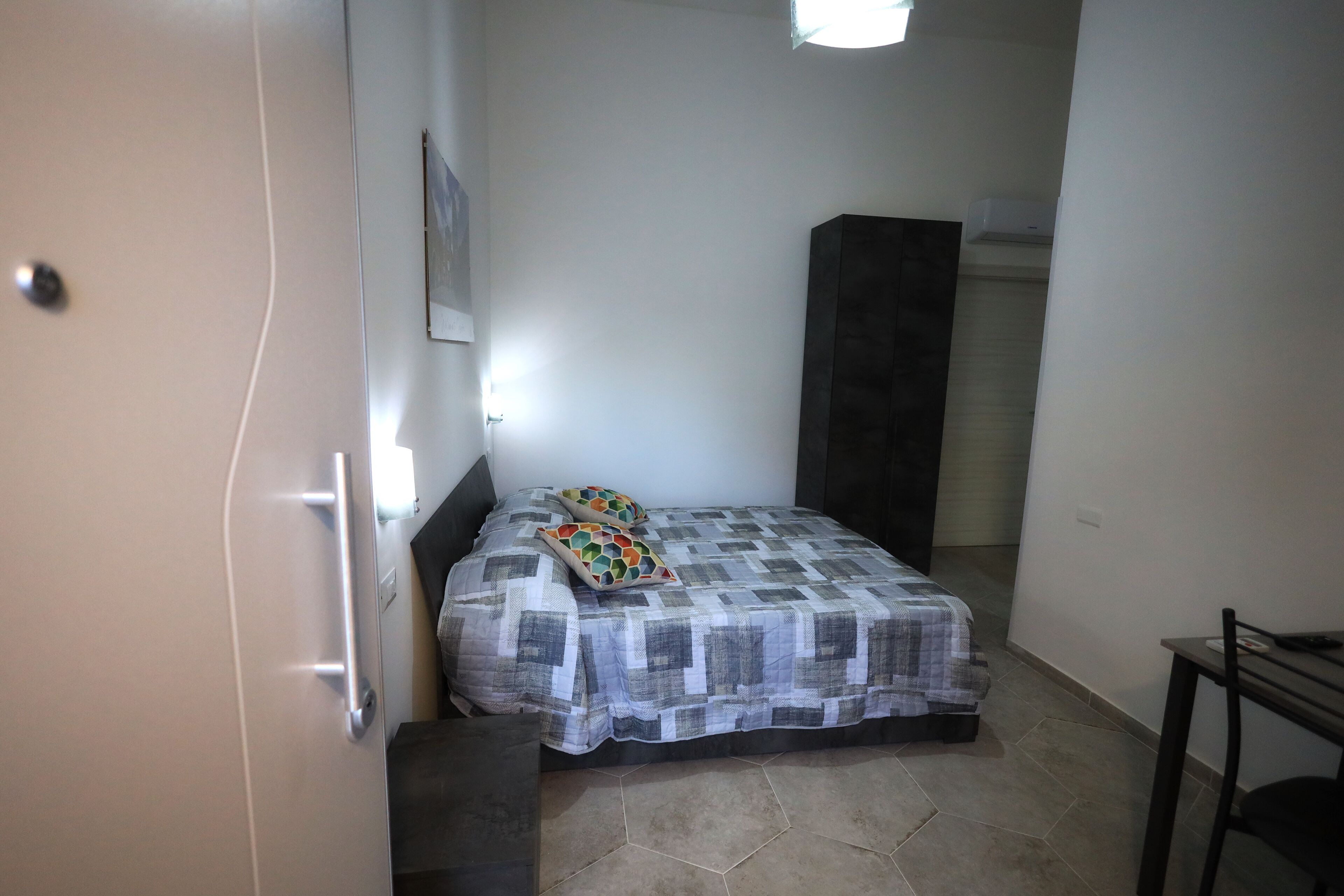 Um quarto pequeno com uma cama, uma escrivaninha e uma cadeira.