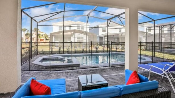 Uma área externa coberta com piscina, espreguiçadeiras e banheira de hidromassagem.