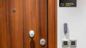 Uma porta de madeira com fechadura, um olho de fechadura e um teclado, e uma placa com a inscrição 'Horizon Gold'.