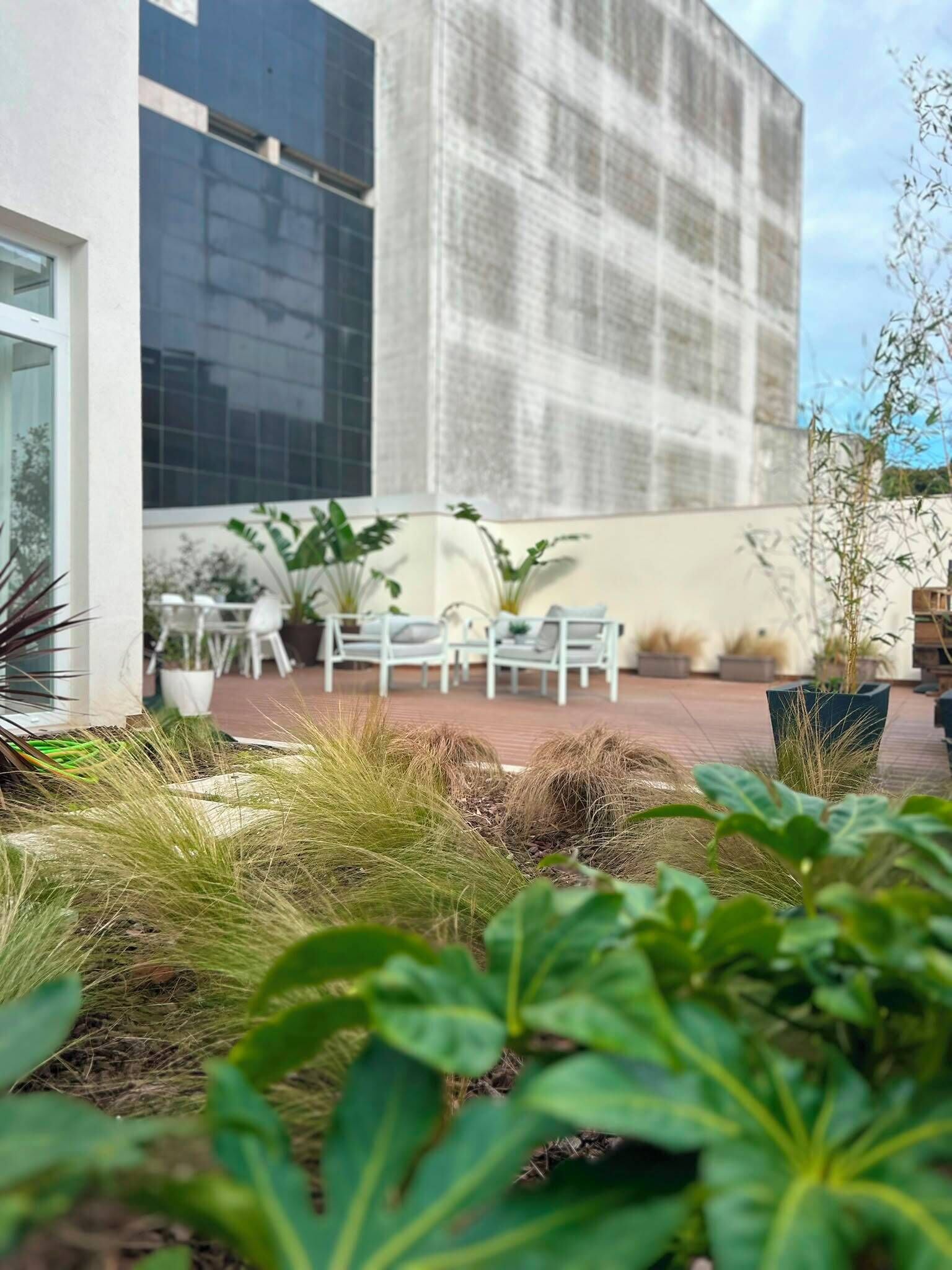 Um edifício moderno com área de pátio, mobiliário de exterior e plantas em vasos.